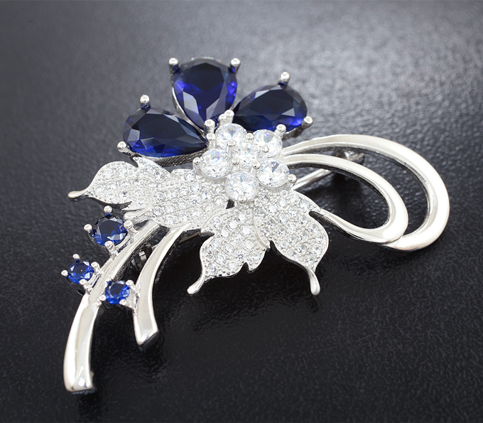 Изысканная серебряная брошь с синим и бесцветным кубиком циркония ...